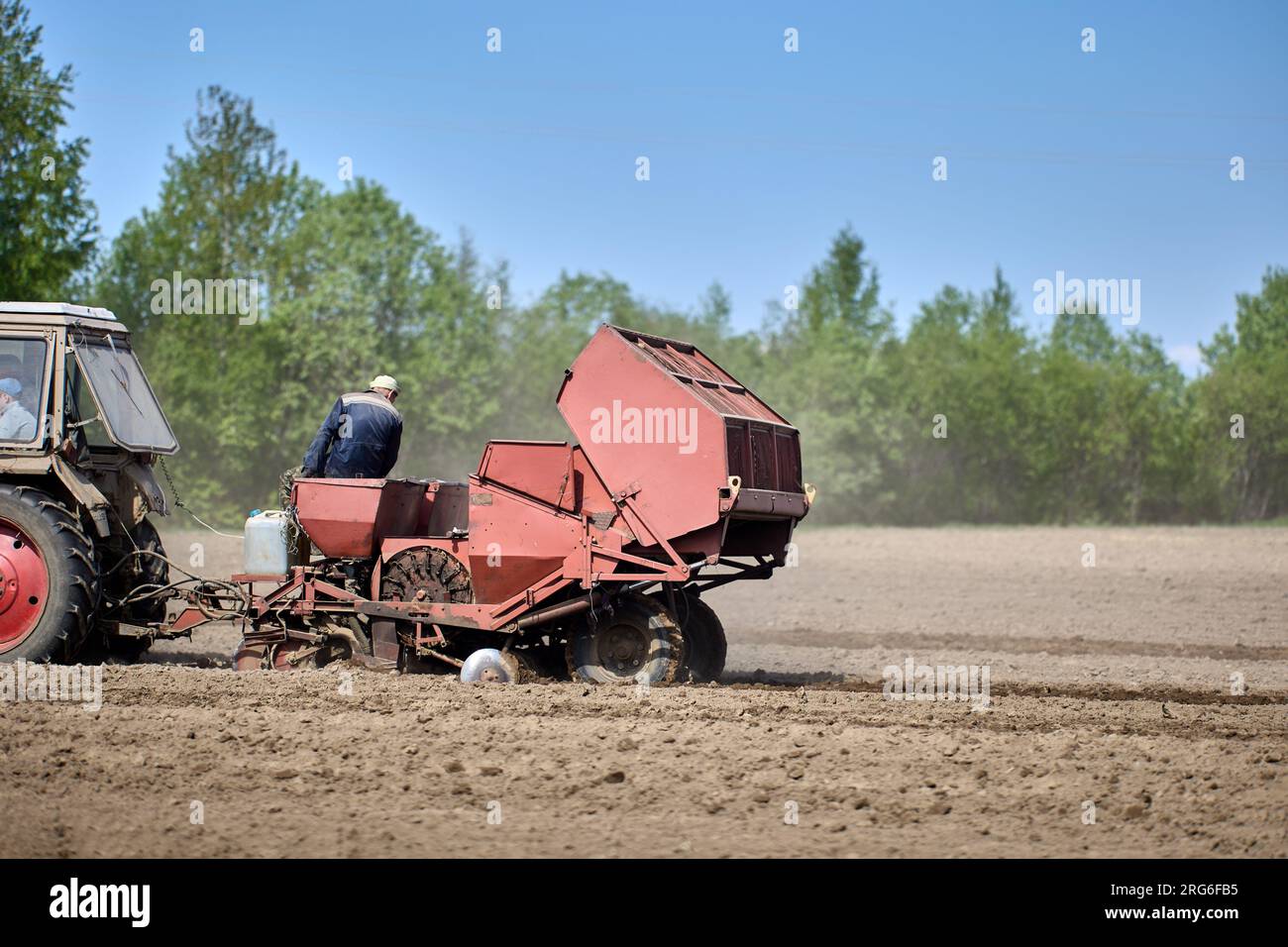 Farmland during planting of potatoes with potato planter hitched to ...