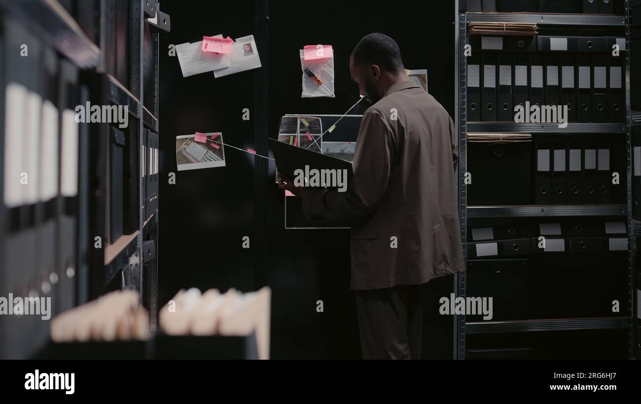 Male detective reading witness statements in archive, using ...
