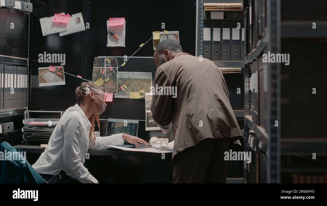 African american detectives looking at photos in police archive, doing ...