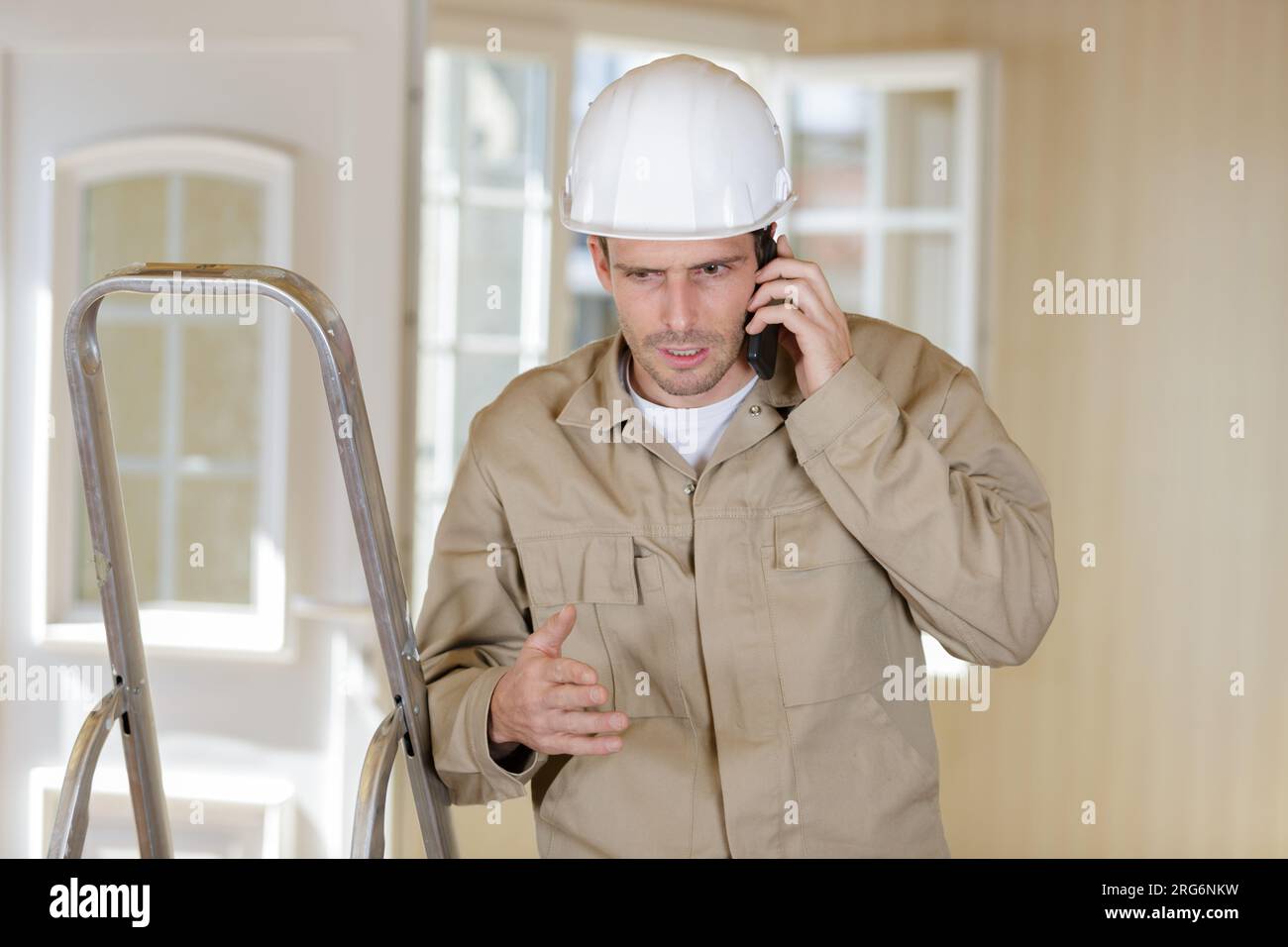 builder on the phone by a ladder Stock Photo - Alamy