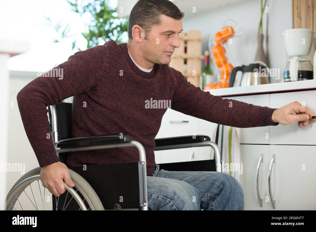 handicapped man sitting on wheelchair in kitchen Stock Photo - Alamy