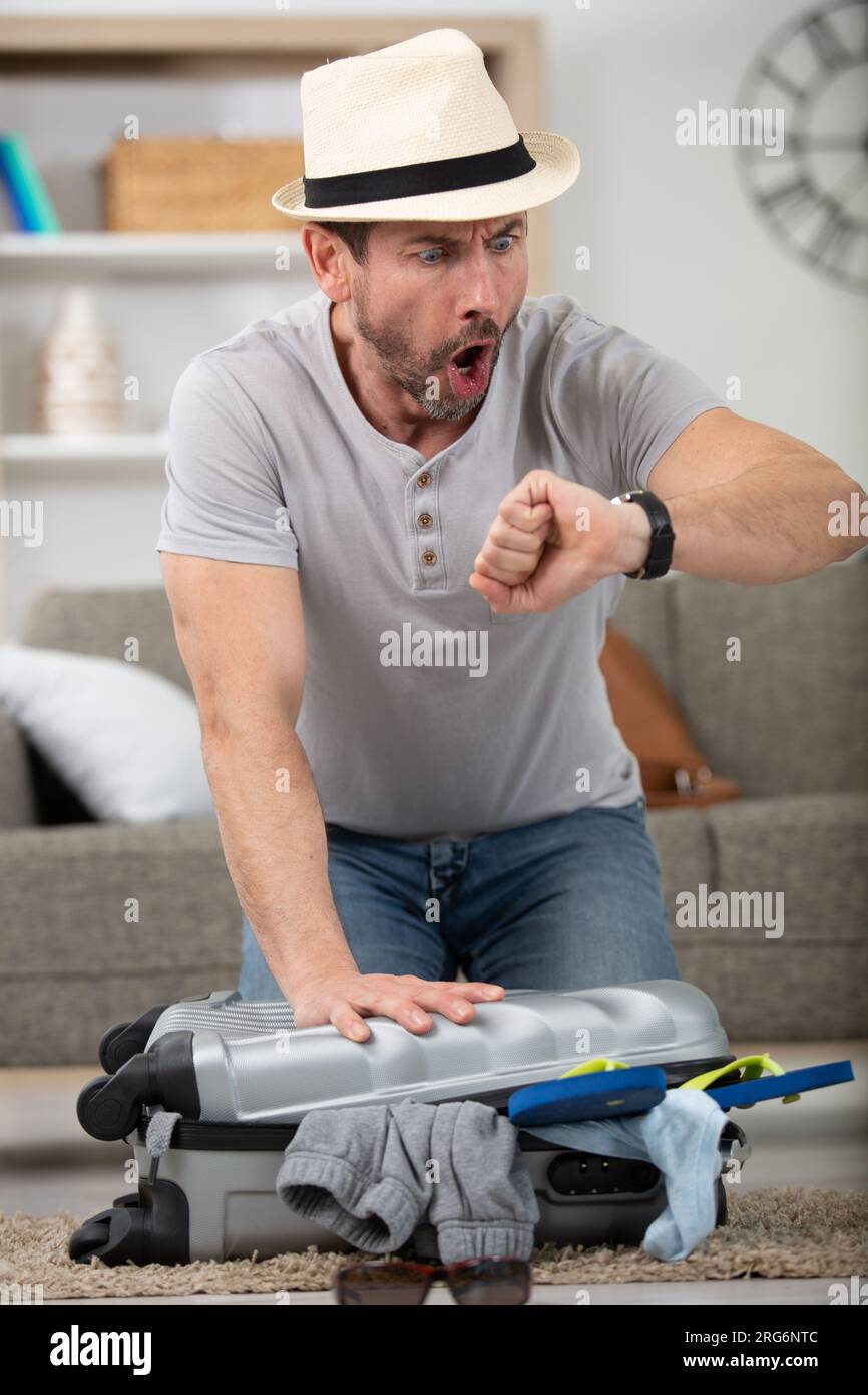 portrait of nervous man packing suitcase looking on clock Stock Photo ...