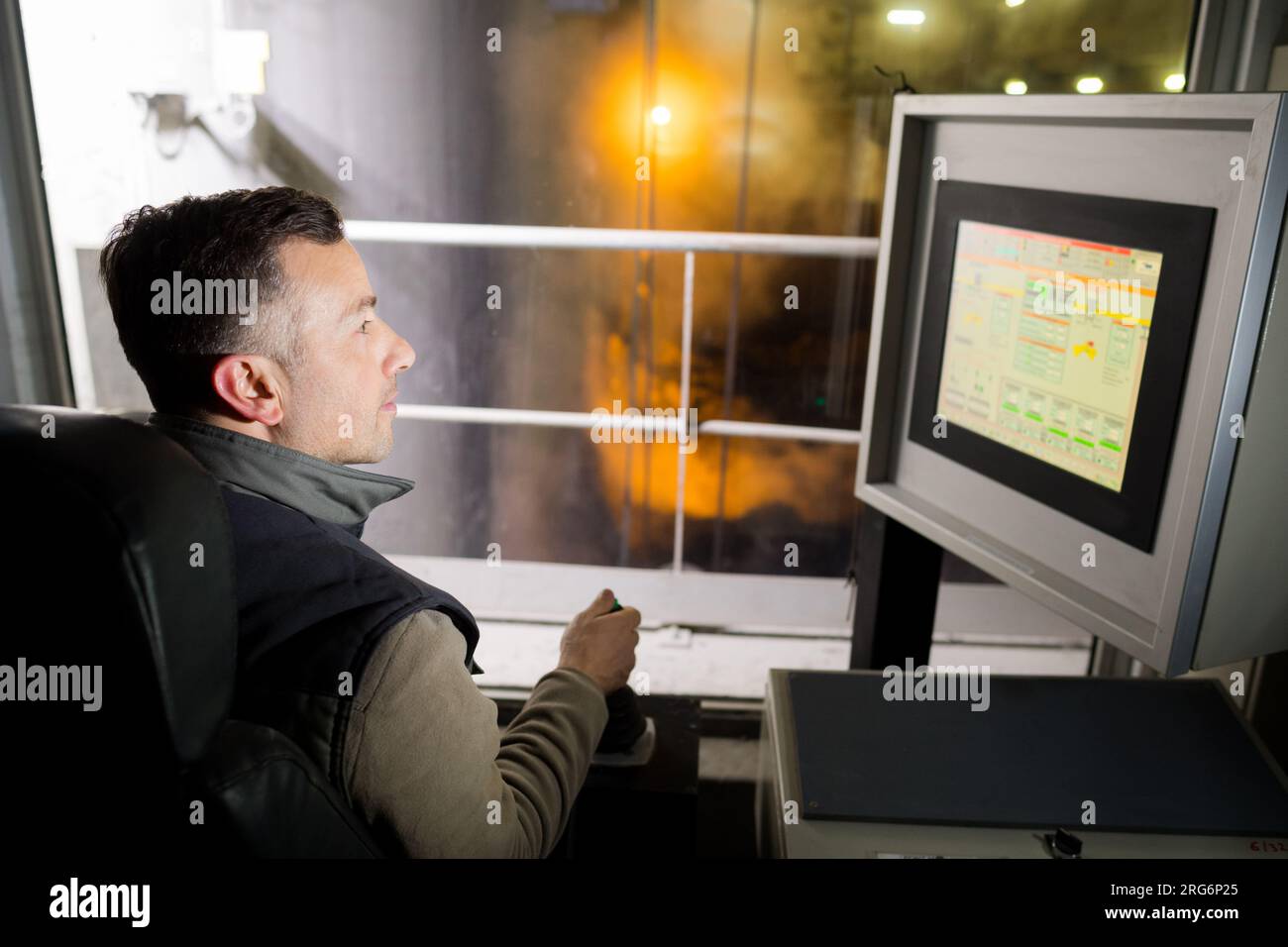 industrial worker by computer monitor overseeing industrial production ...
