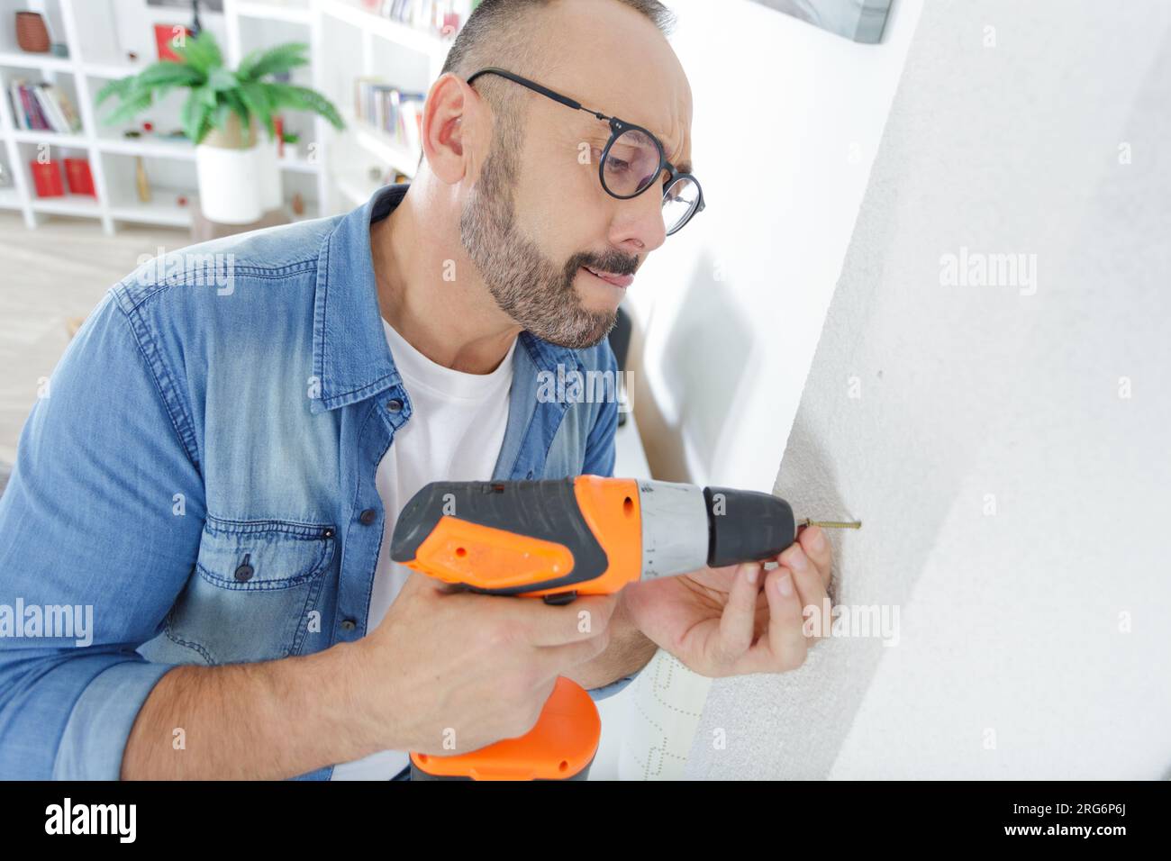 man using power drill on wall at home Stock Photo - Alamy