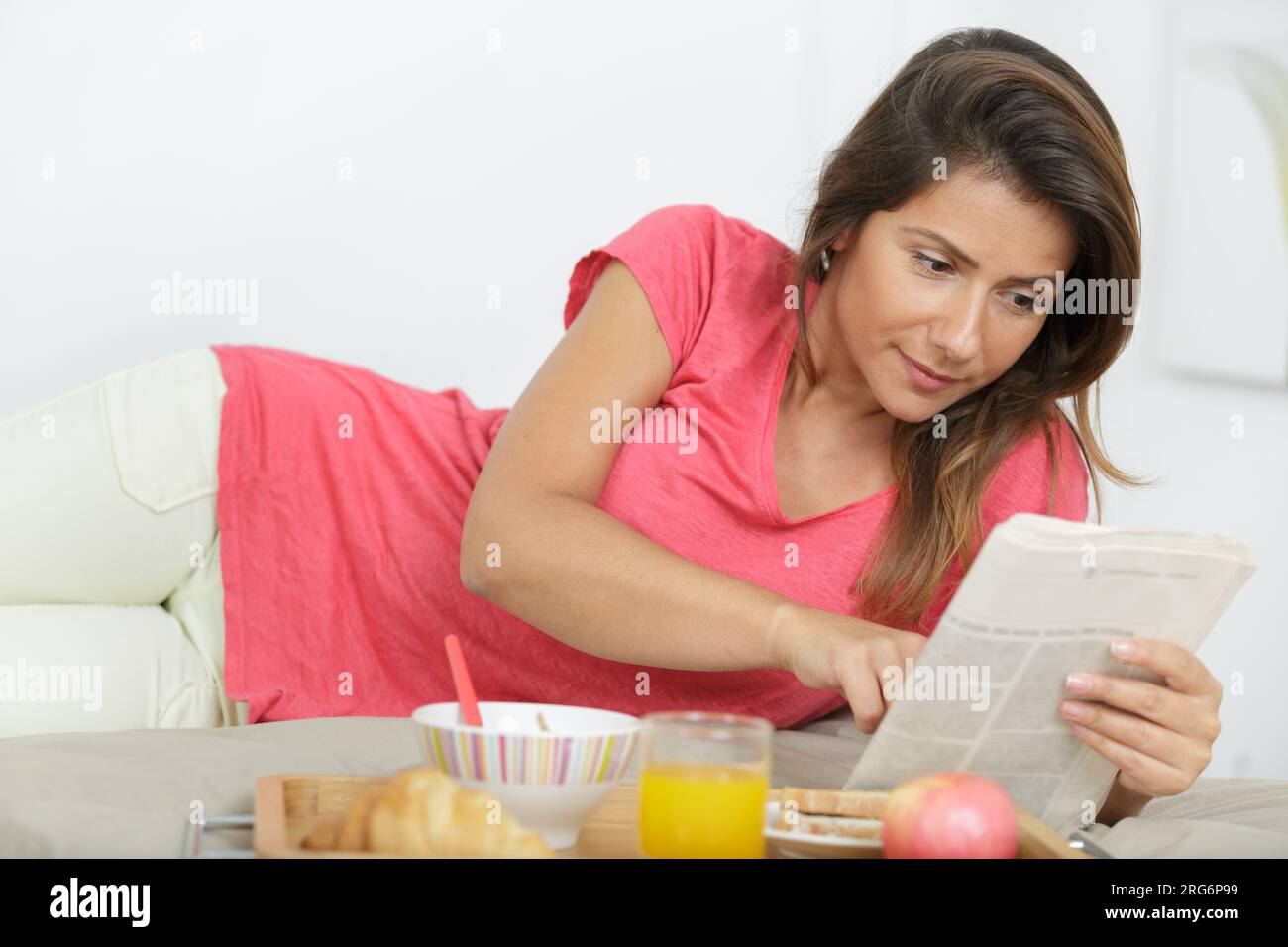 woman reading the newspaper layed on bed with breakfast tray Stock ...