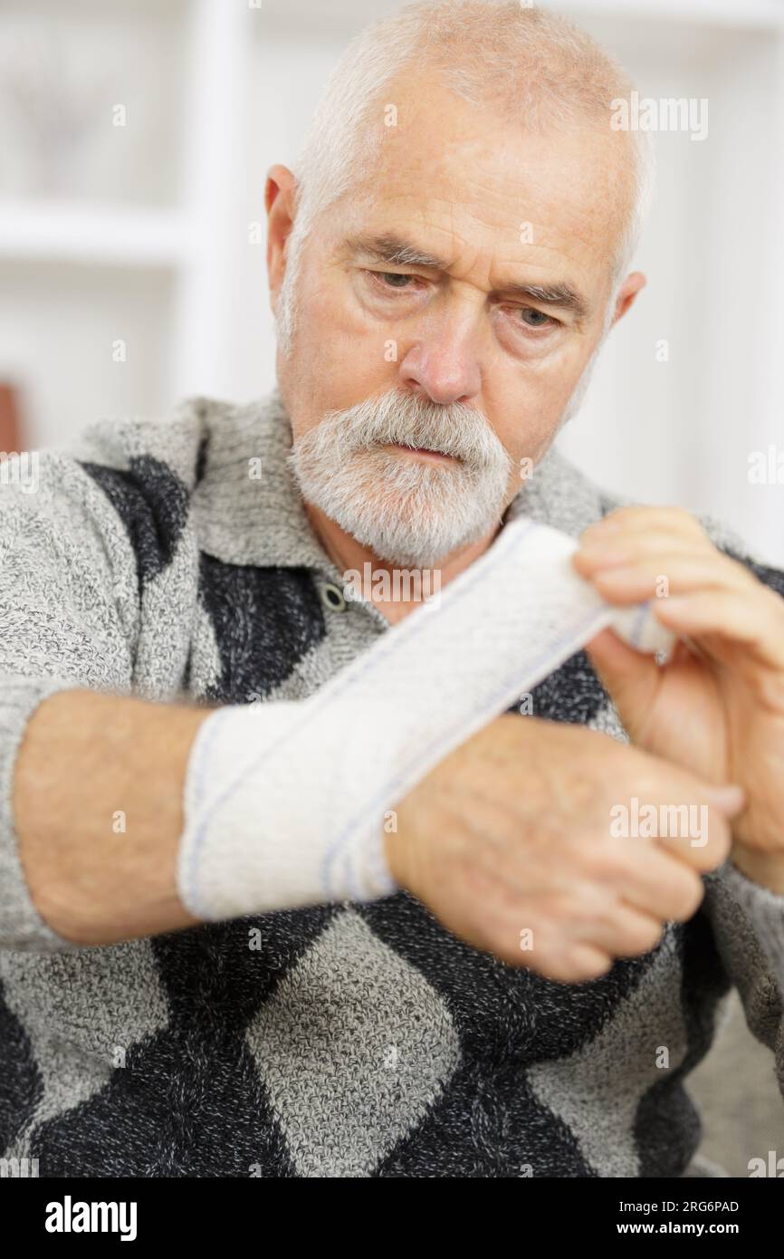 elderly man sitting on sofa with hand injured Stock Photo - Alamy