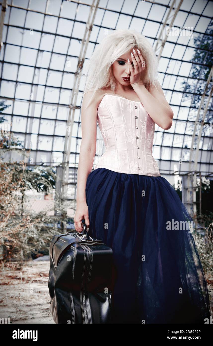 Portrait of the sad freak girl with old suitcase. Beautiful strange ...