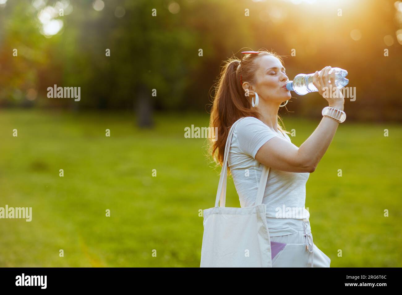 Summer time. elegant woman in white shirt with tote bag drinking water ...