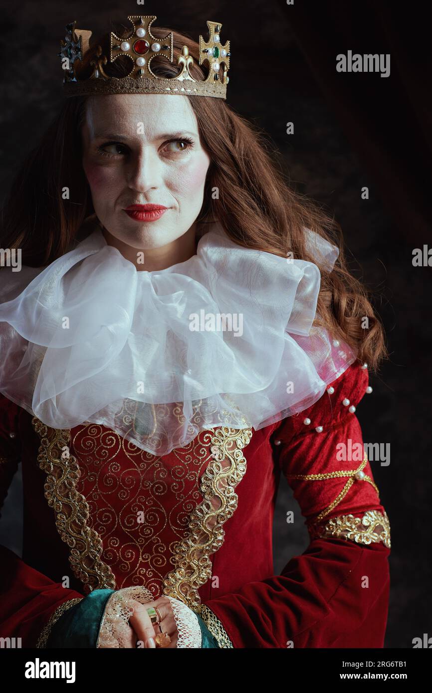 Pensive Medieval Queen In Red Dress With White Collar And Crown On Dark
