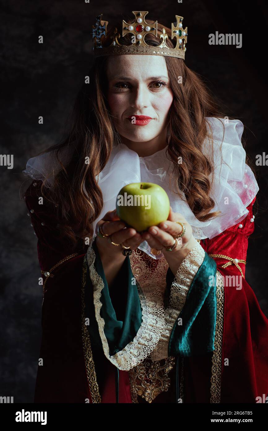 medieval queen in red dress with green apple, white collar and crown on ...