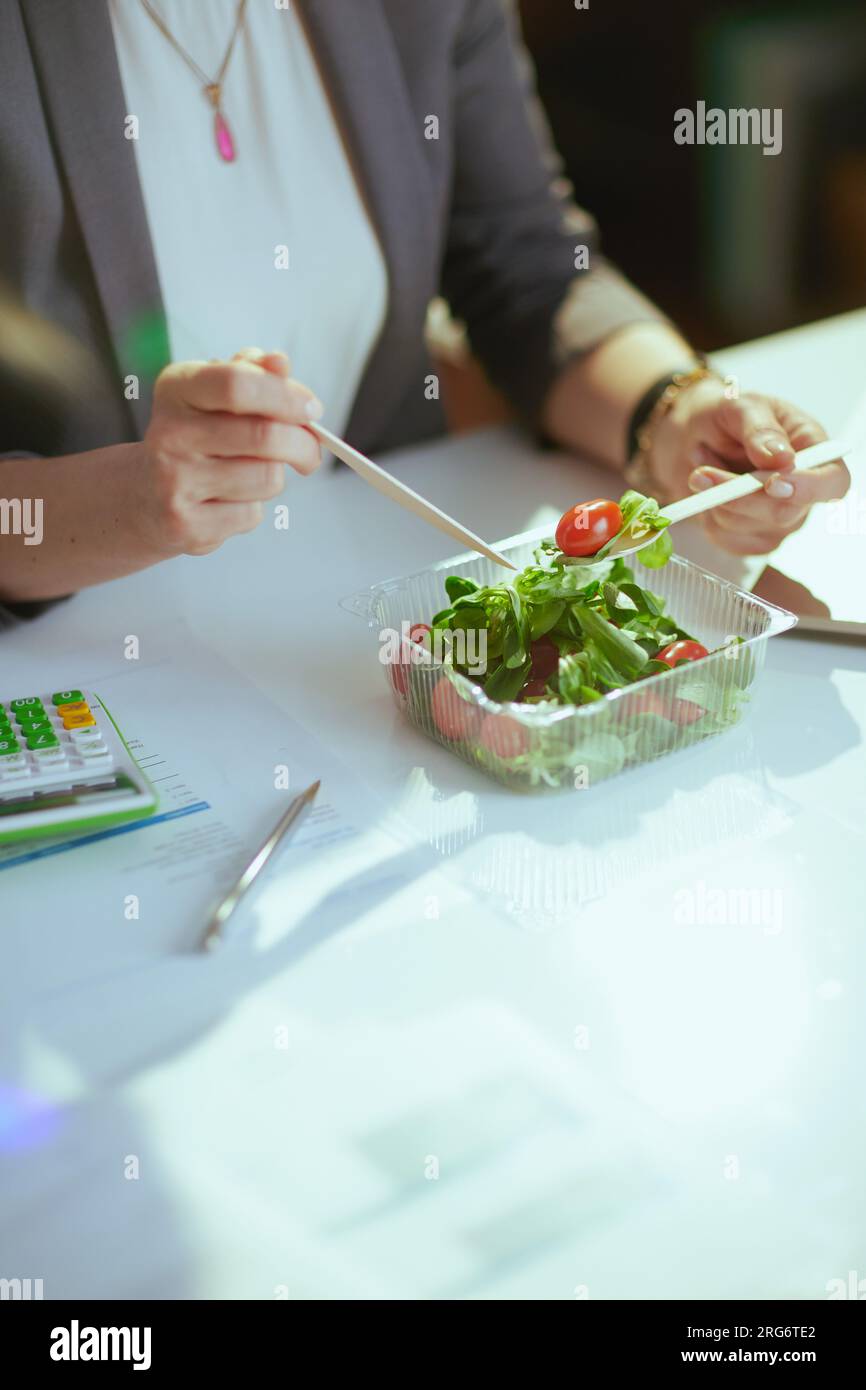 Sustainable workplace. Closeup on woman employee in green office eating ...
