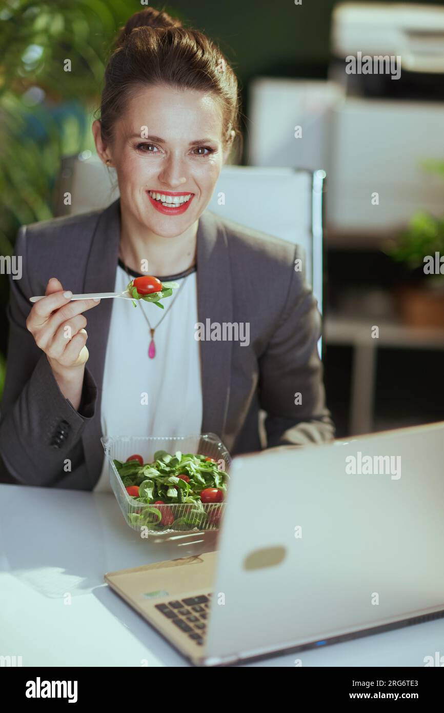 Sustainable workplace. smiling modern female employee in a grey ...