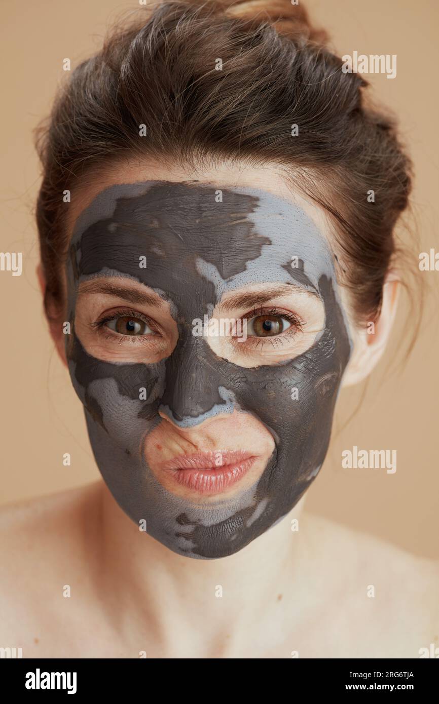 doubting middle aged woman with facial mask isolated on beige ...