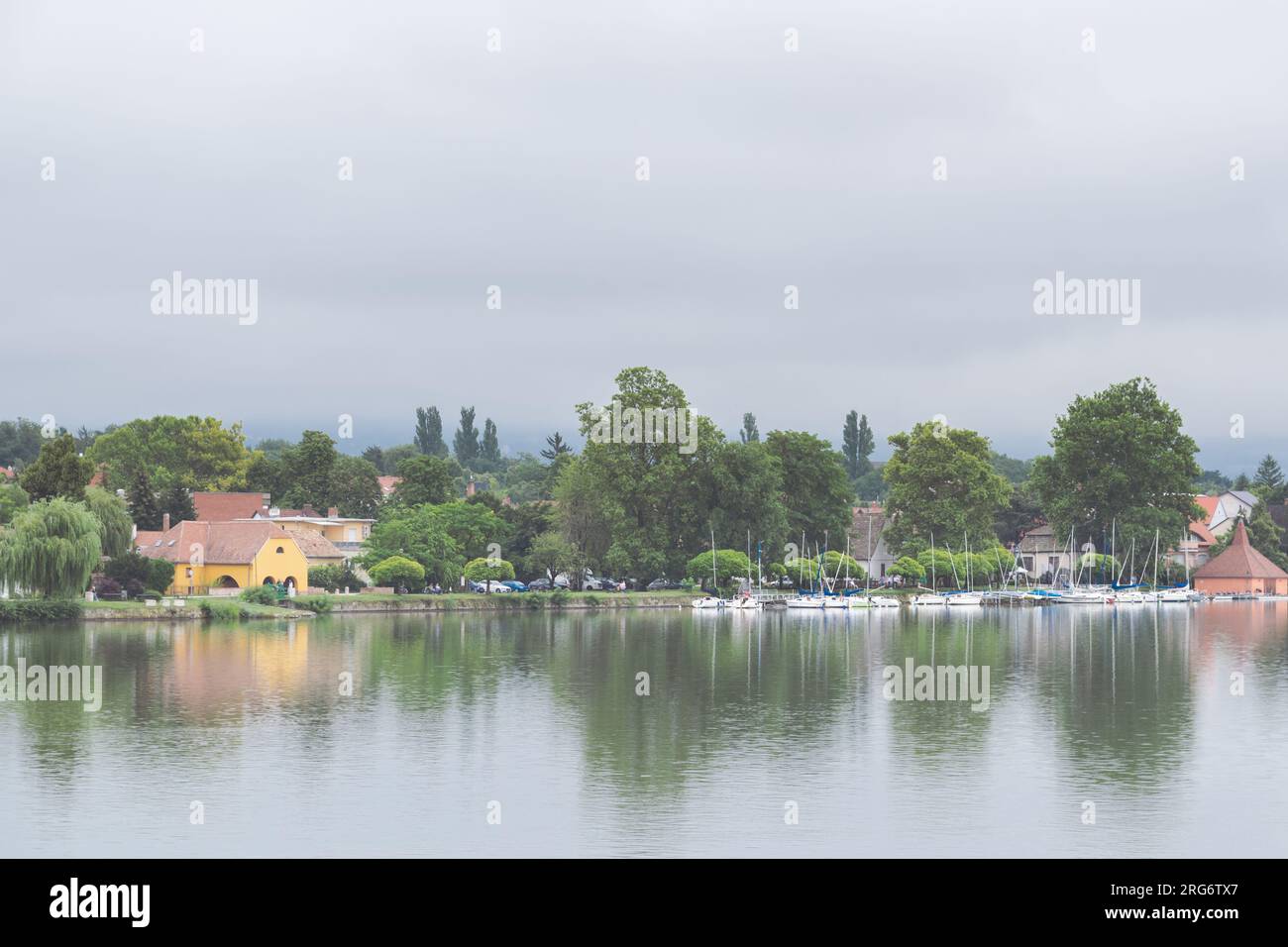 View of Old Lake in Tata with trees, buildings and boats on the shore ...
