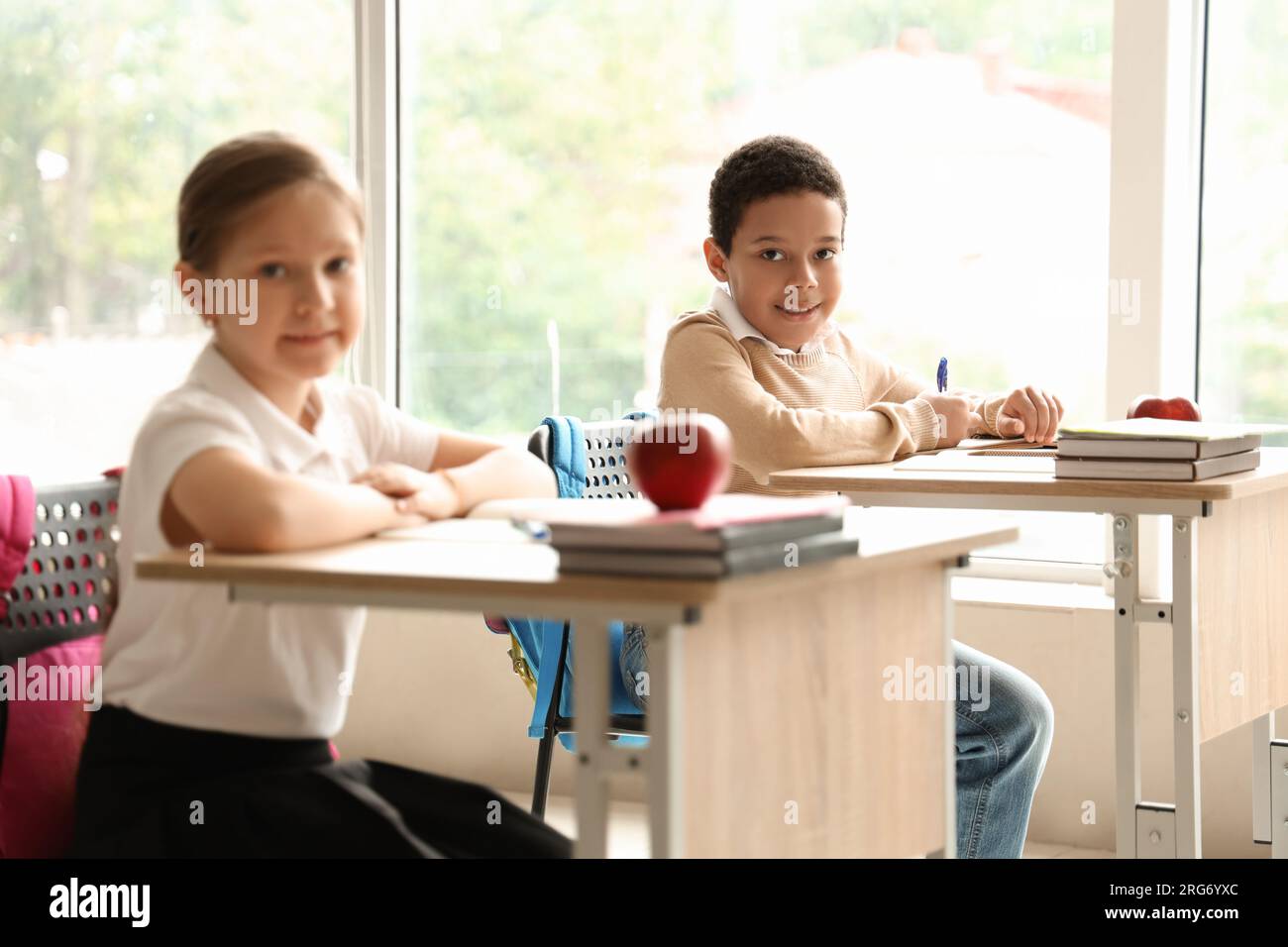 Little students sitting at desks in classroom Stock Photo - Alamy