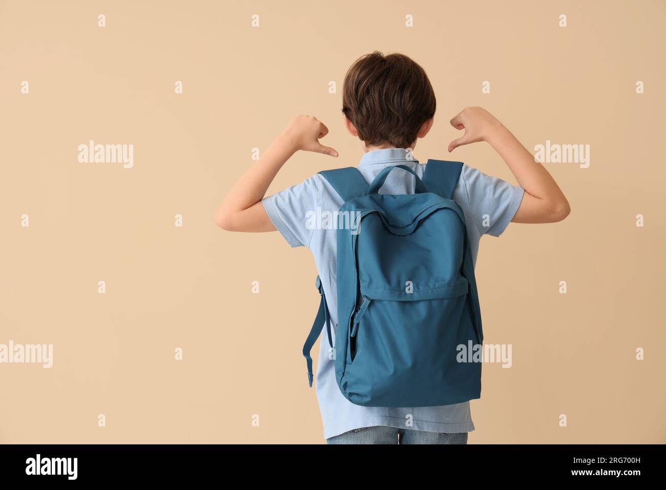 Little boy pointing at backpack on beige background, back view Stock ...