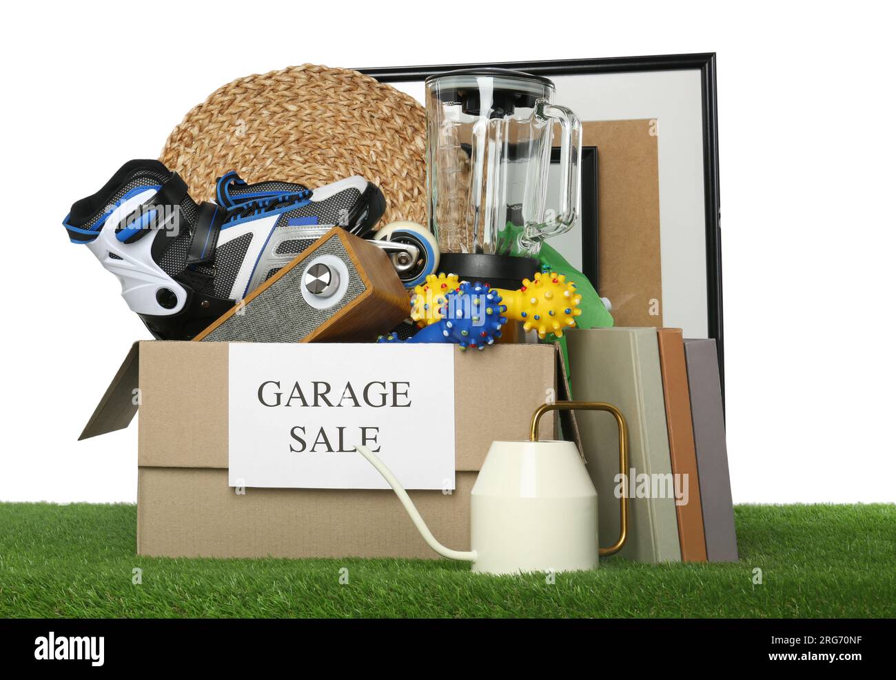 Box with sign Garage Sale and different stuff on green grass against ...