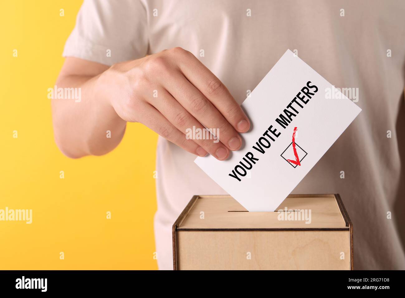 Man putting paper with text Your Vote Matters and tick into ballot box ...