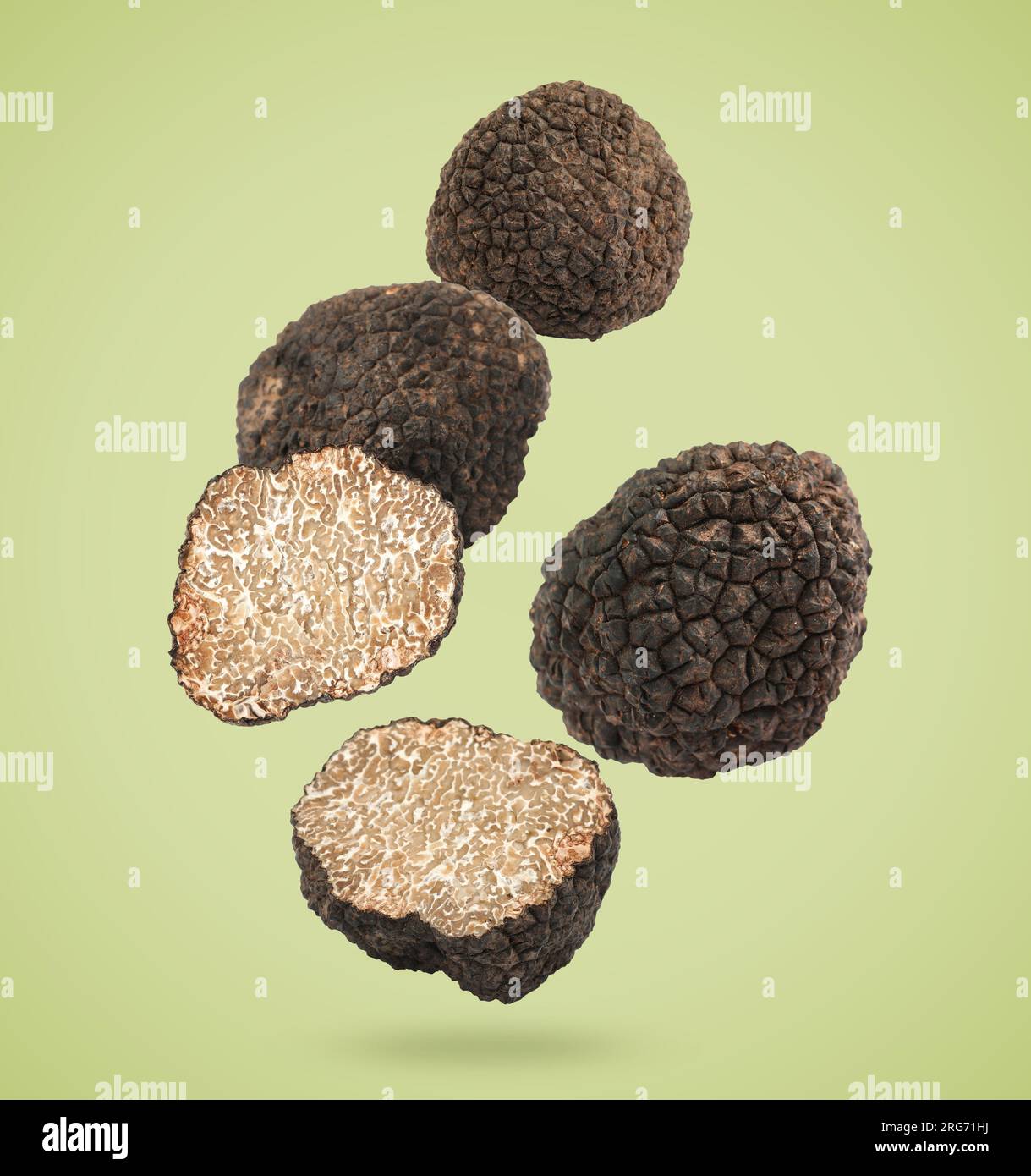 Cut and whole truffles falling on olive color background Stock Photo ...