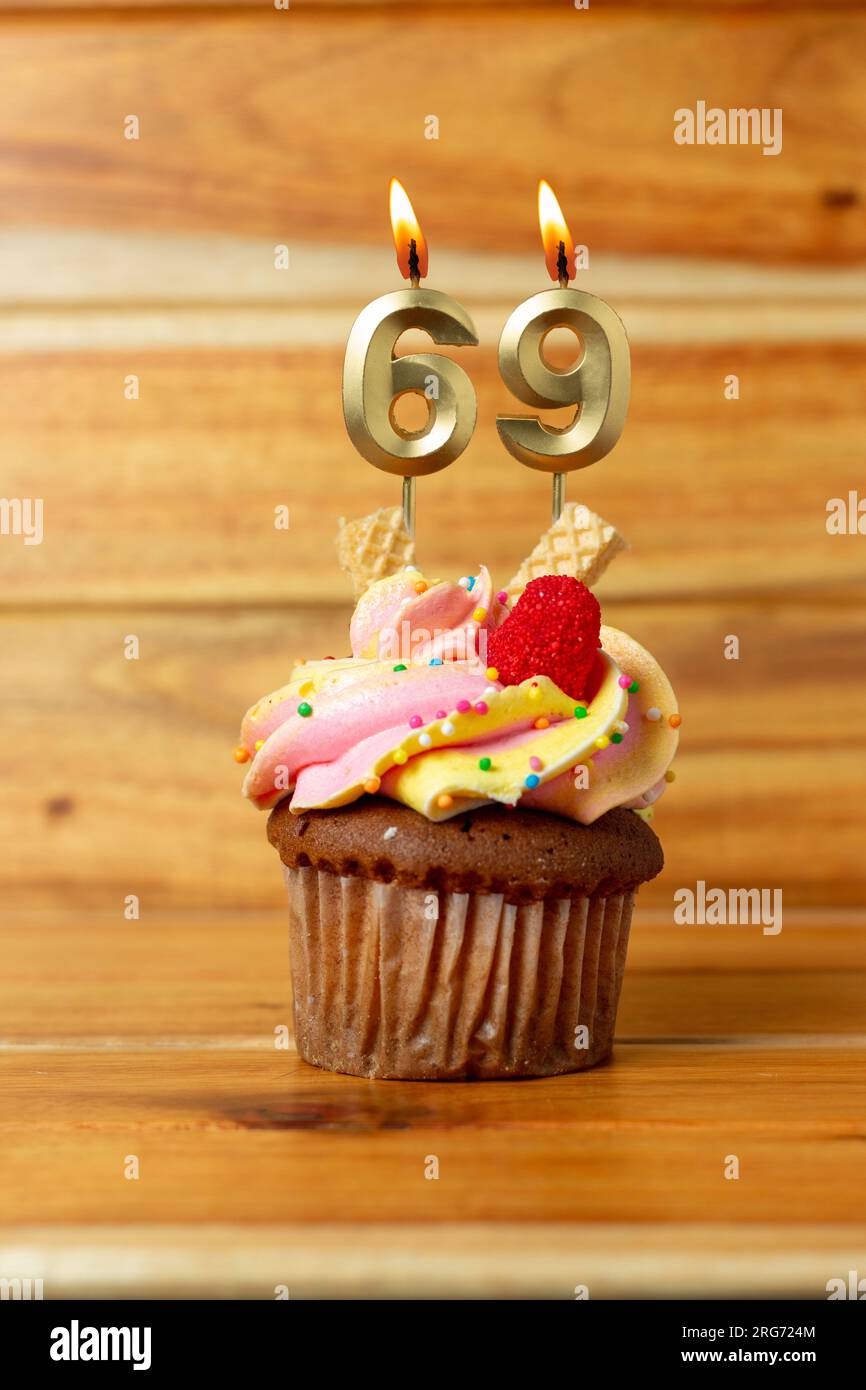 Golden birthday candle on wooden background - Birthday cupcake with ...