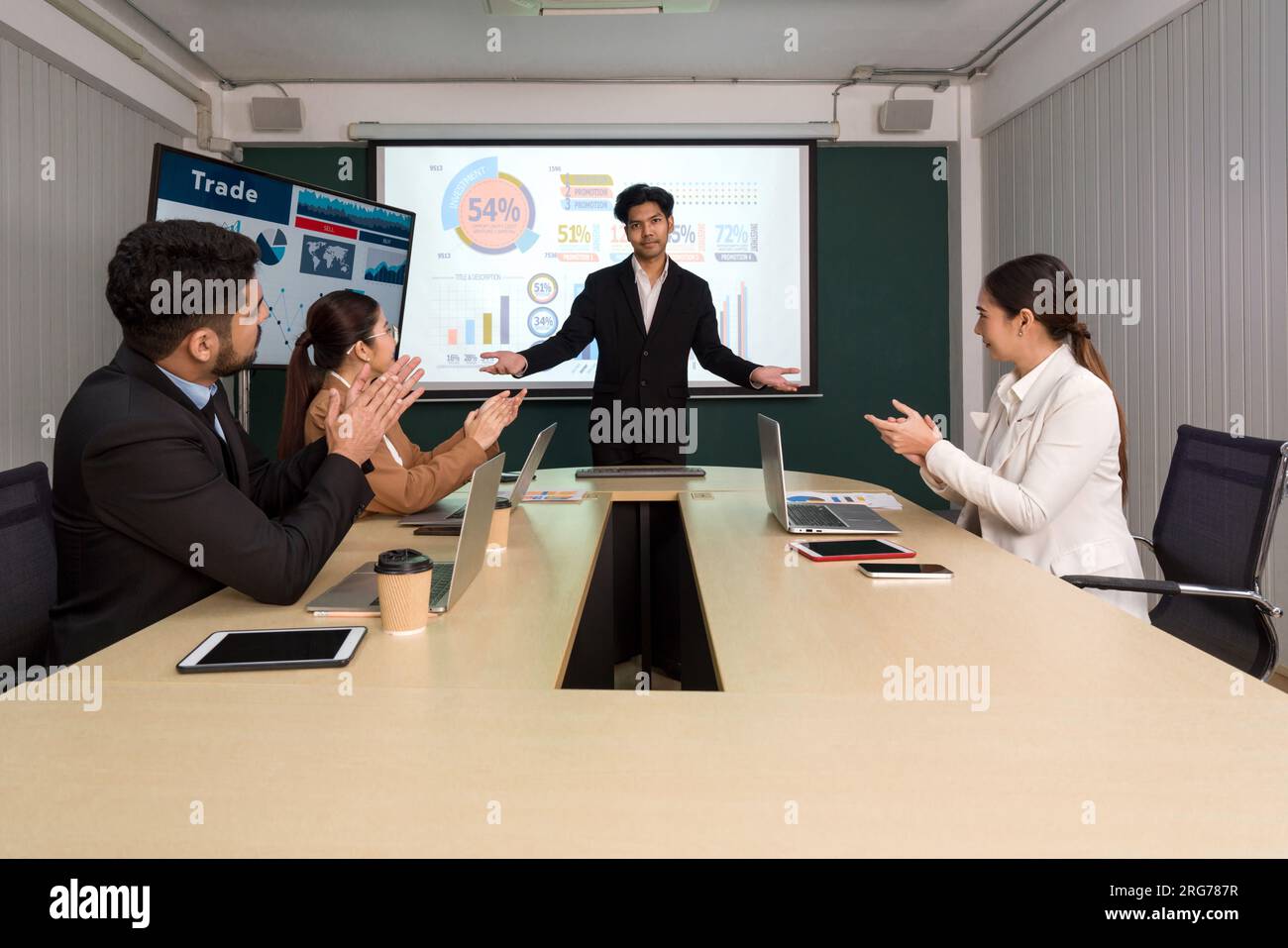 Enthusiastic diverse corporate team applauding in a meeting around a ...