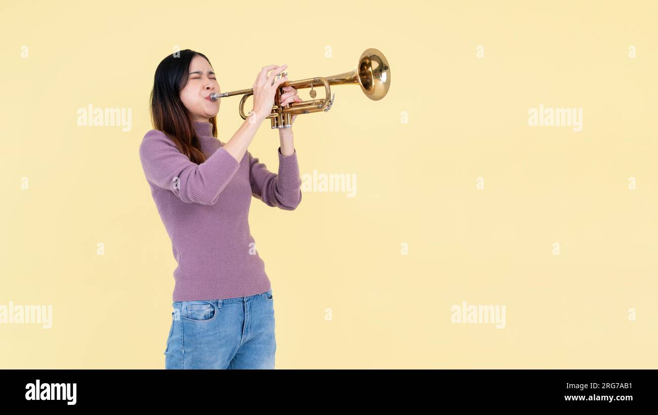 A beautiful and talented Asian woman is playing the trumpet while ...