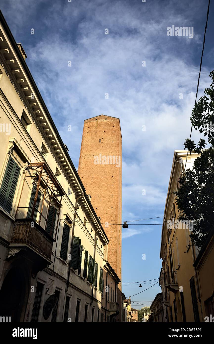 Tower on a street with a tree top of a garden framed by buildings in an ...