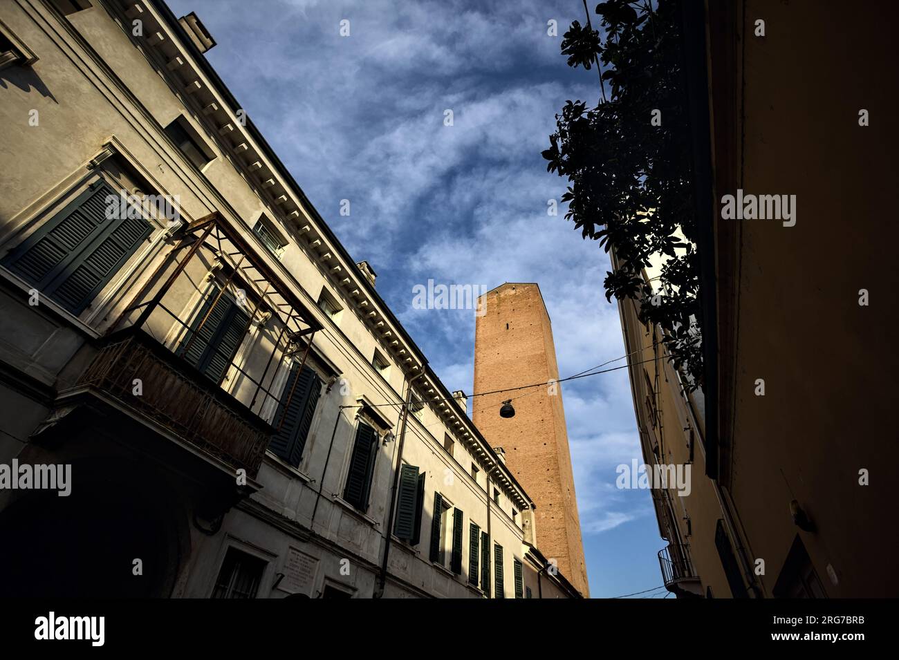 Tower on a street with a tree top of a garden framed by buildings in an ...