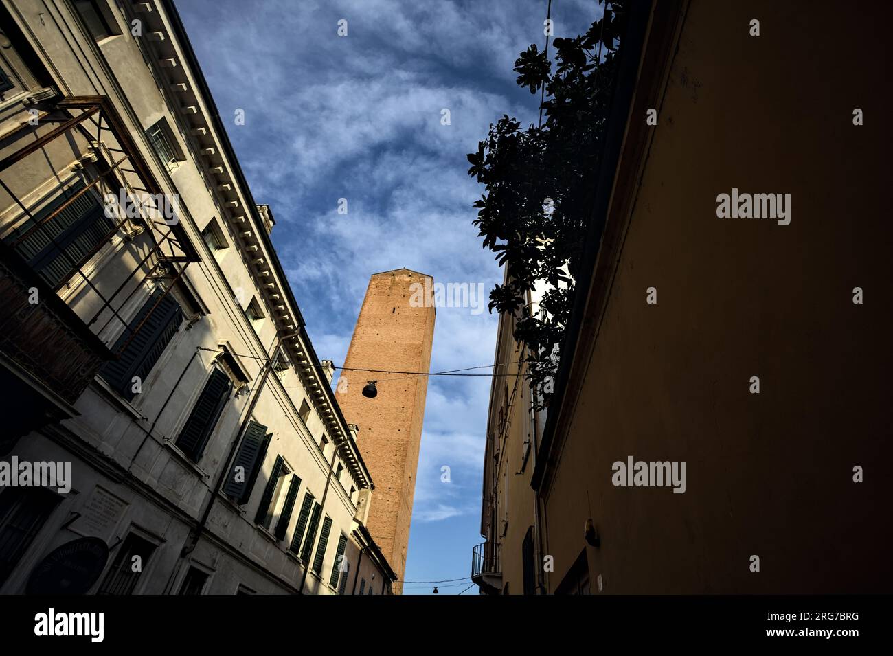 Tower on a street with a tree top of a garden framed by buildings in an ...