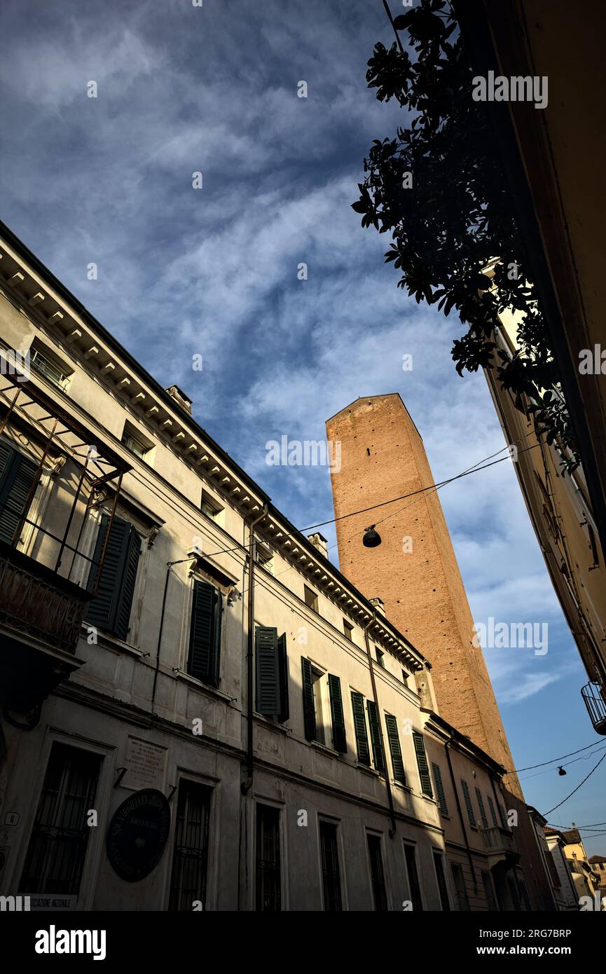 Tower on a street with a tree top of a garden framed by buildings in an ...