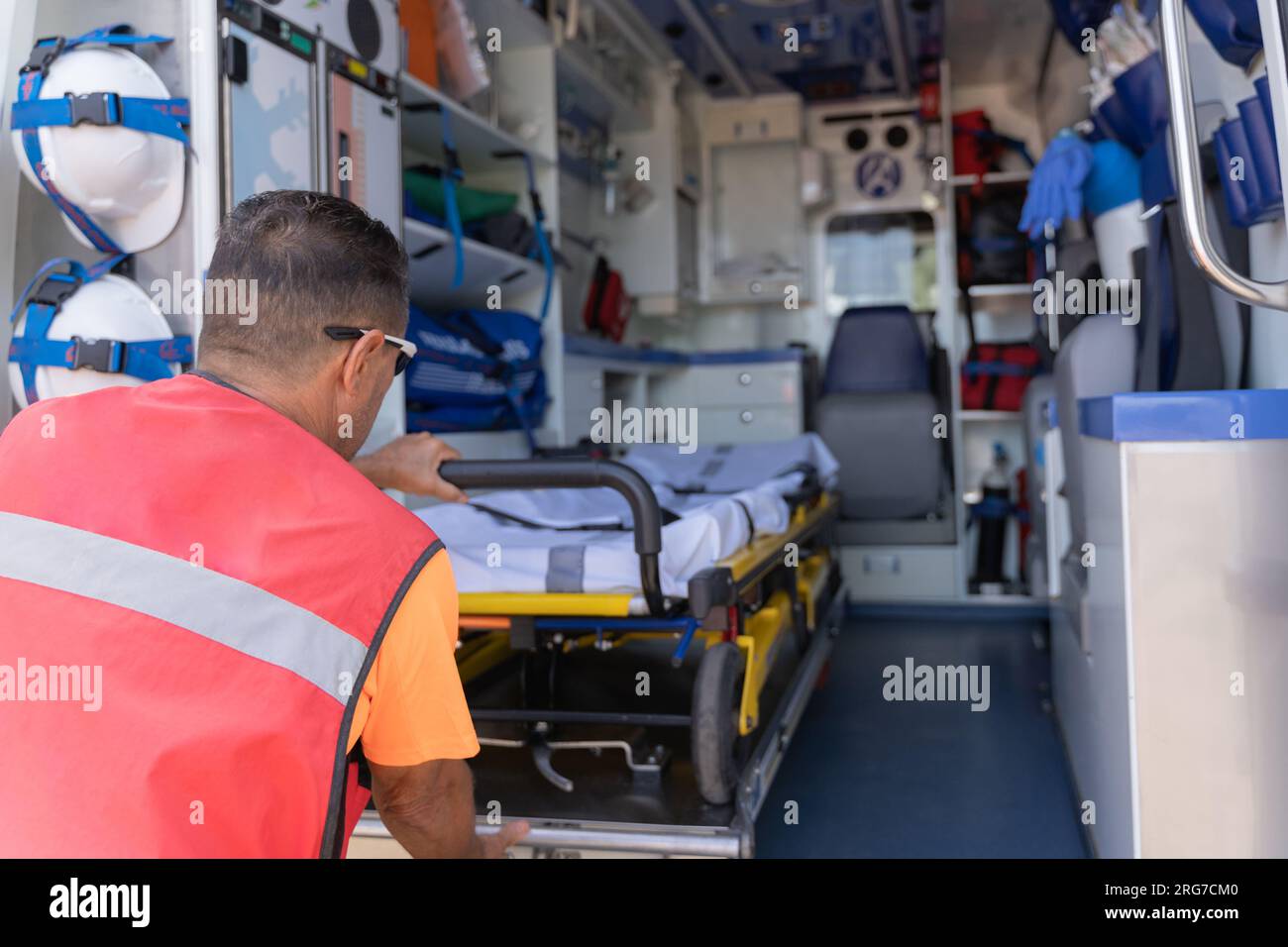 Rear view of a male member of the medical staff taking a stretcher out ...