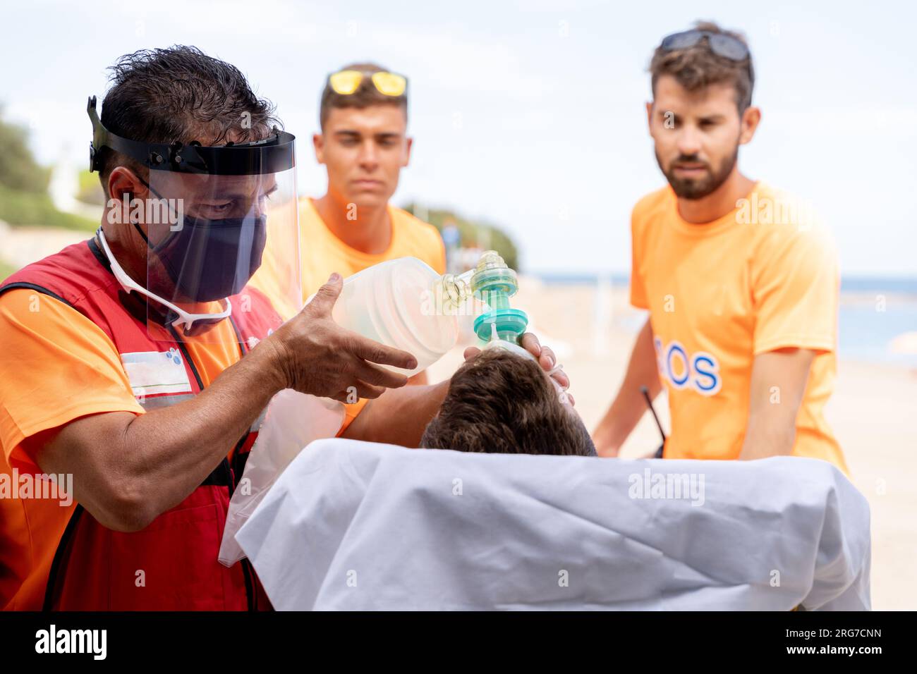 Doctors attending to an injured person on the beach with an oxygen tank ...