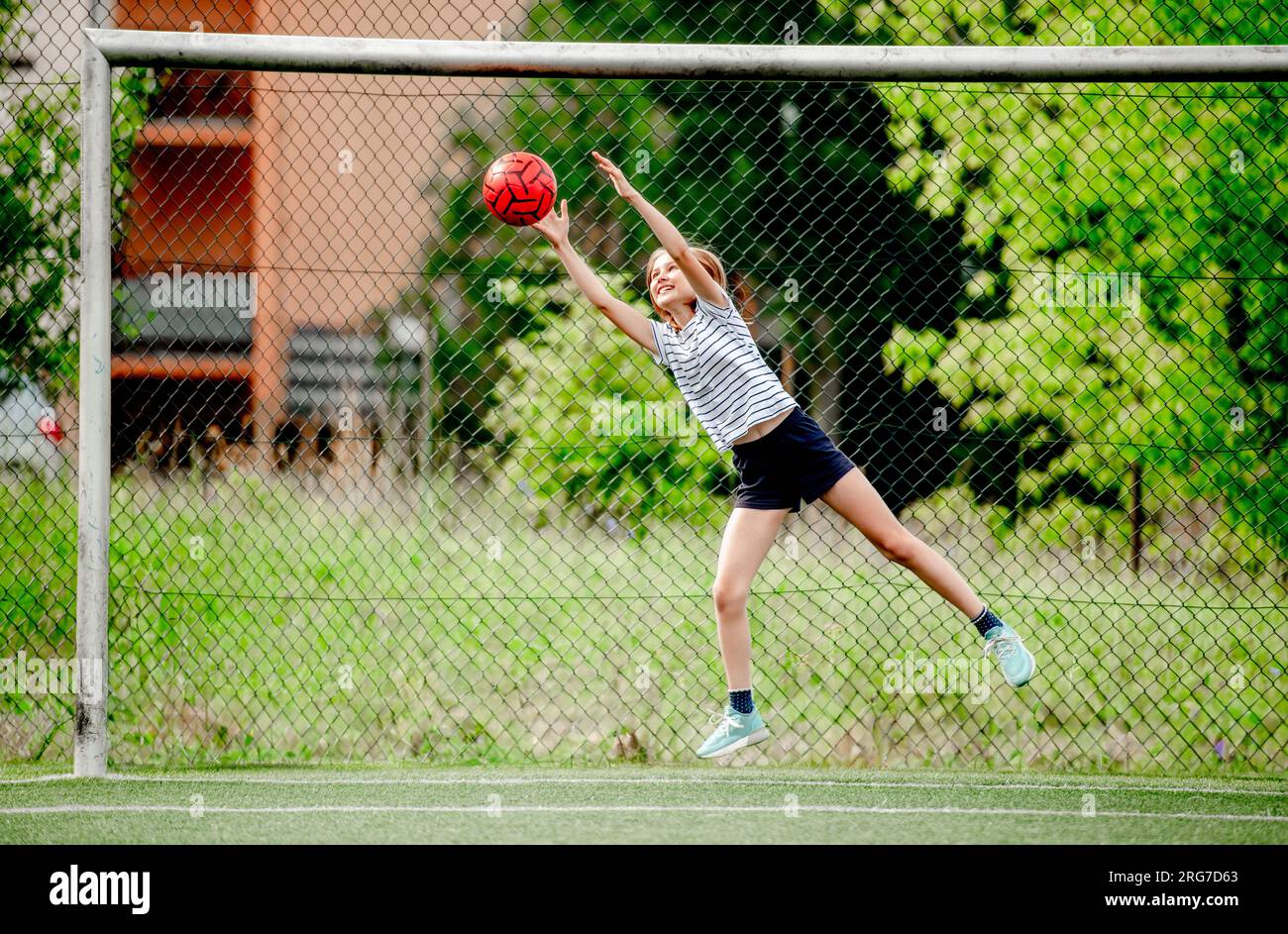 Pretty child girl catching football ball defending goal. Cute female ...