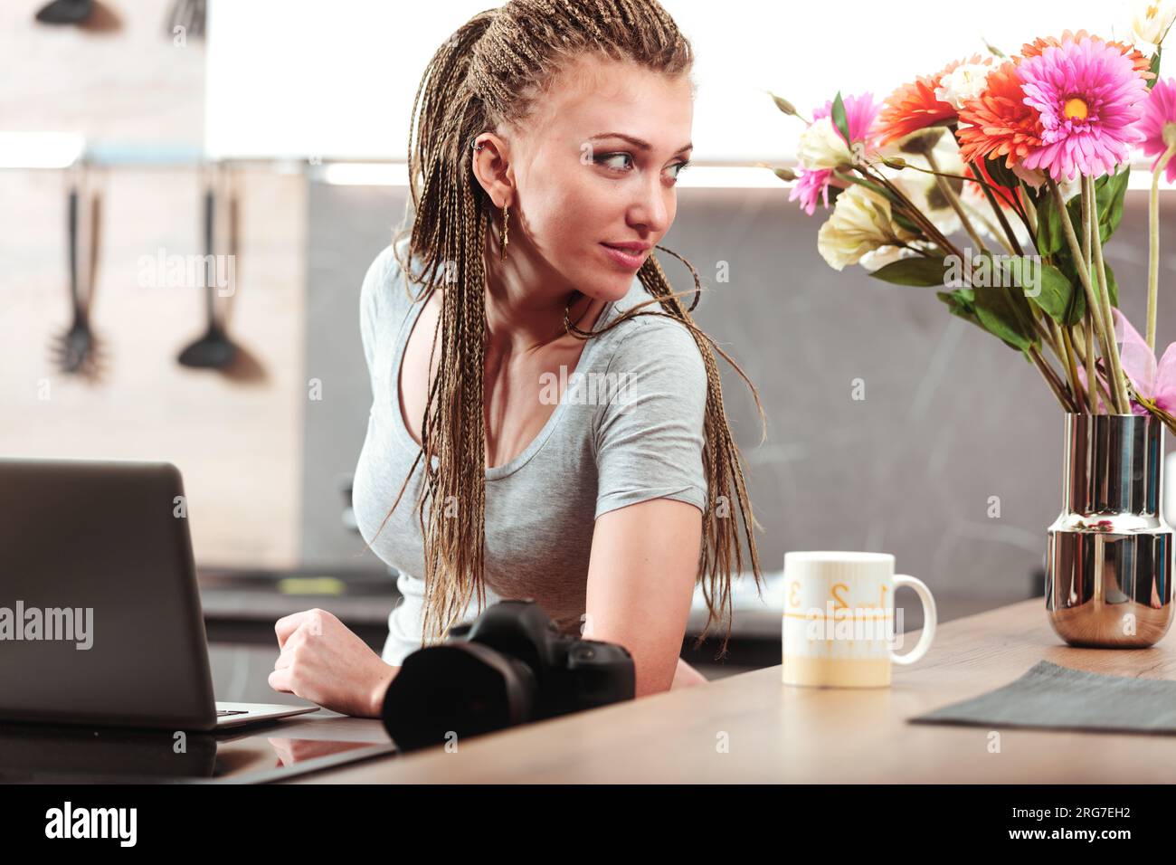 Artistic woman with box-braids uses DSLR and laptop, perfecting skills ...
