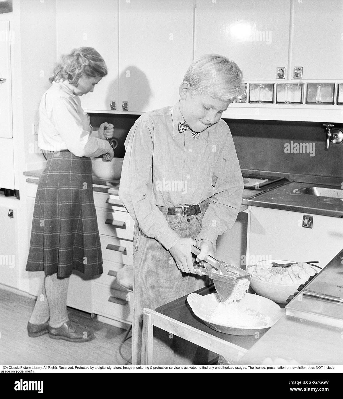 In the 1950s. A teenage boy and girl are cooking in the kitchen. He ...