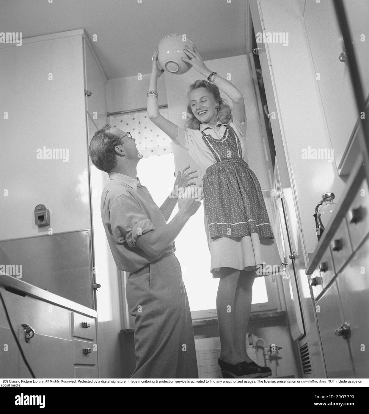 In the 1940s. A couple looking happy when playing around in the kitchen ...