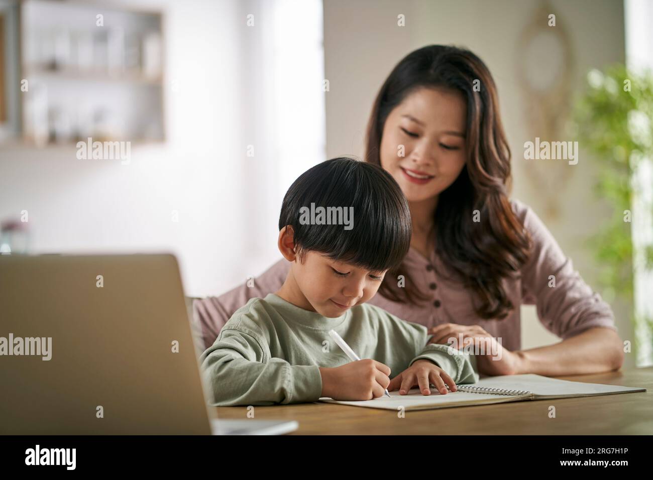 young asian mother sitting at table at home helping son with his study Stock Photo - Alamy