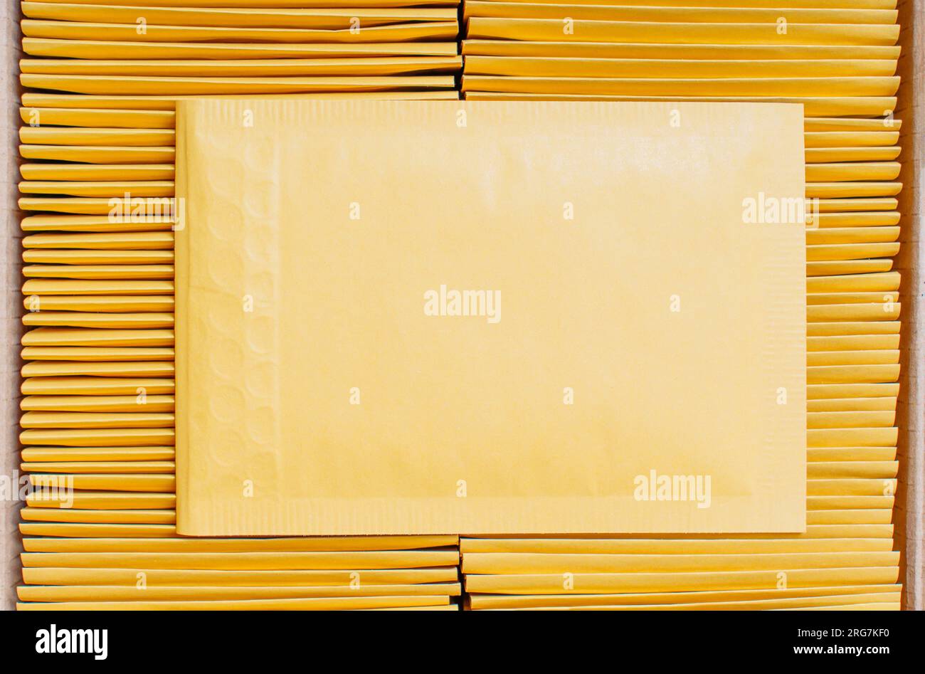 Yellow padded mailer placed on top of a shipping box filled with neatly ...