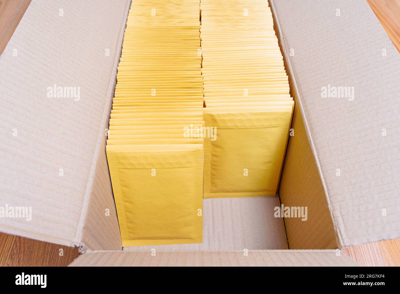 Two rows of yellow bubble mailers neatly packed in a cardboard box ...