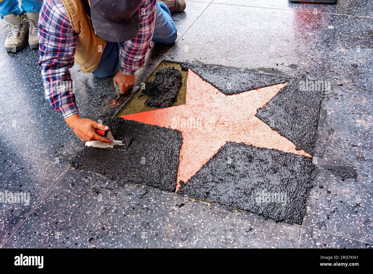 Worker levels the terrazzo pavement mixture around a coral star on the ...