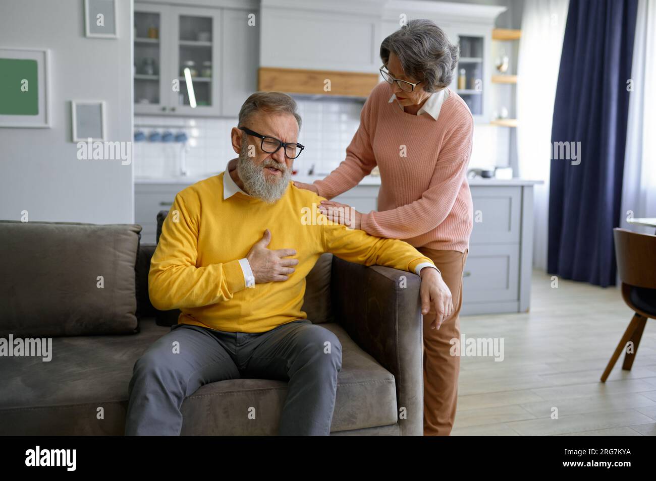Senior man touching chest having heart attack and his wife supporting ...