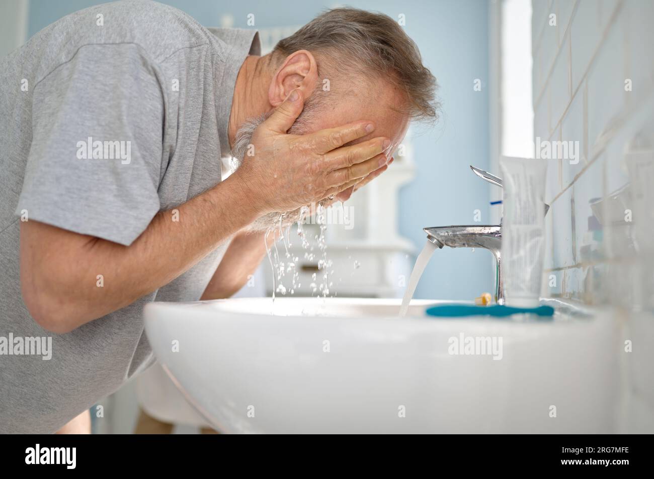 Senior man washing face at sink in home bathroom Stock Photo - Alamy