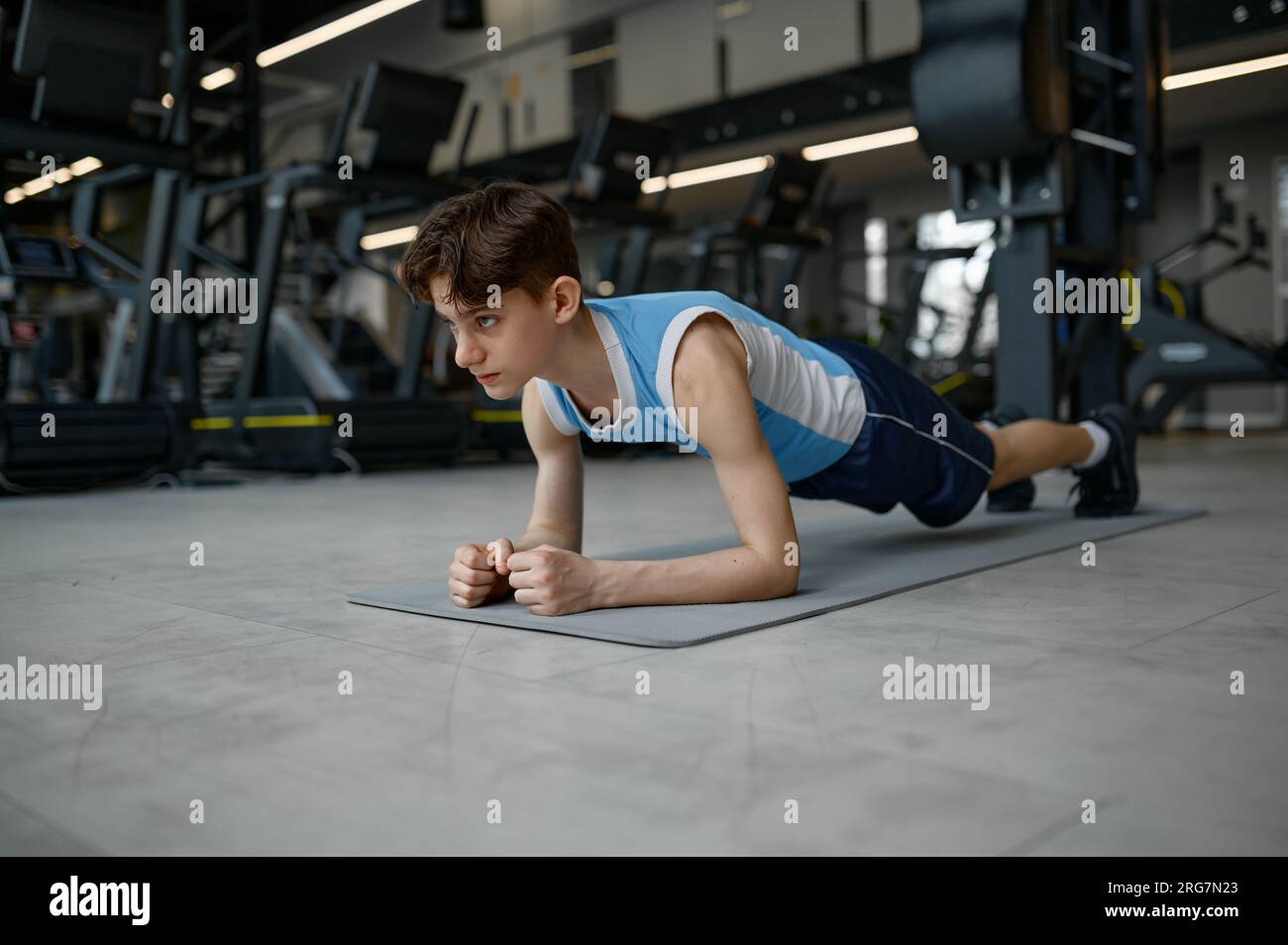 Teenager sport boy standing in plank doing training exercise for muscle ...