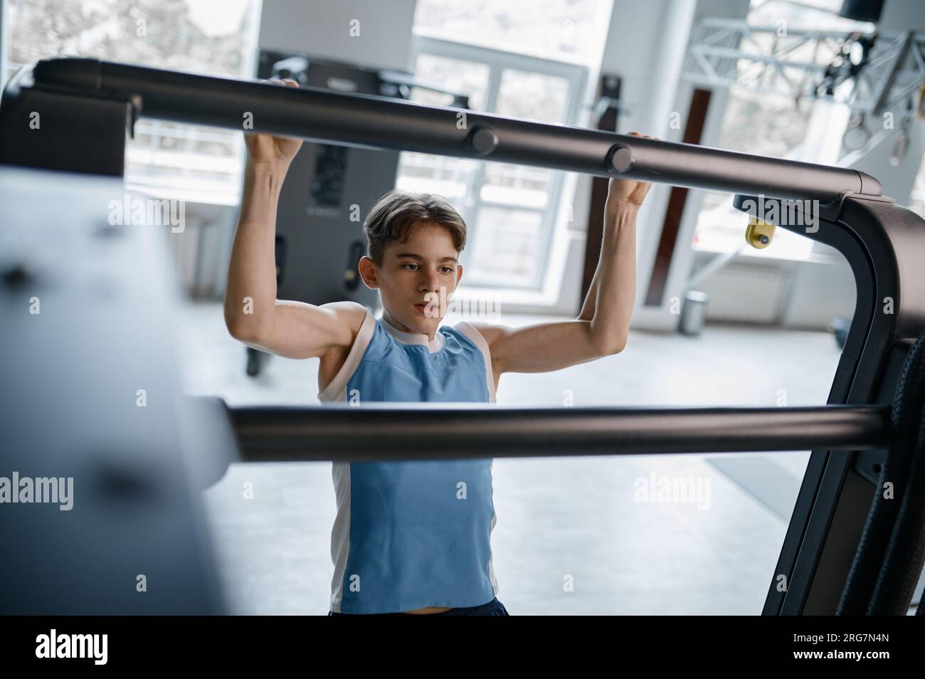 Teenager boy pulling up on crossbar closeup shot over gym background ...