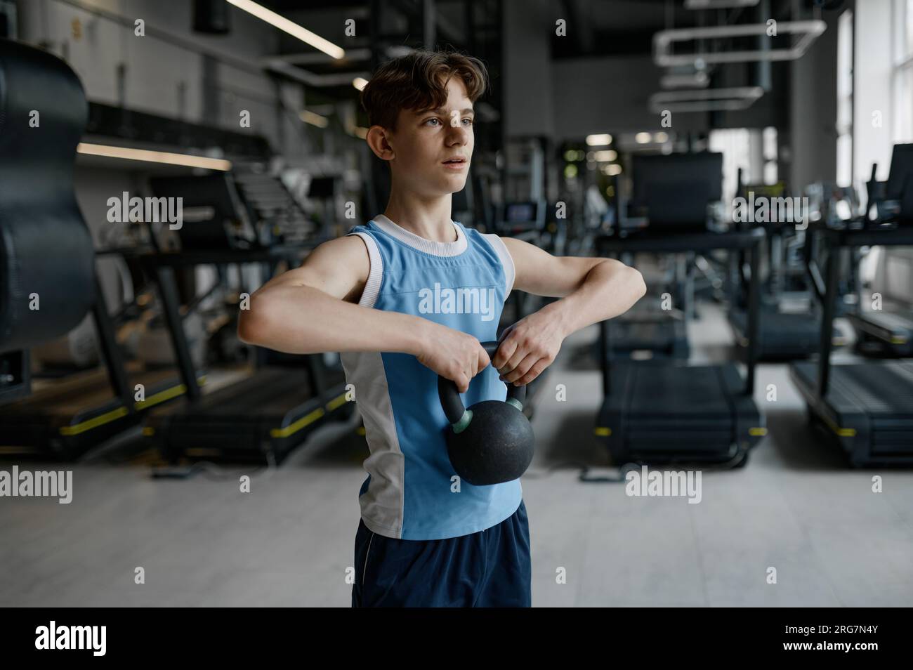 Closeup young sportive boy training with weights lifting kettlebell ...