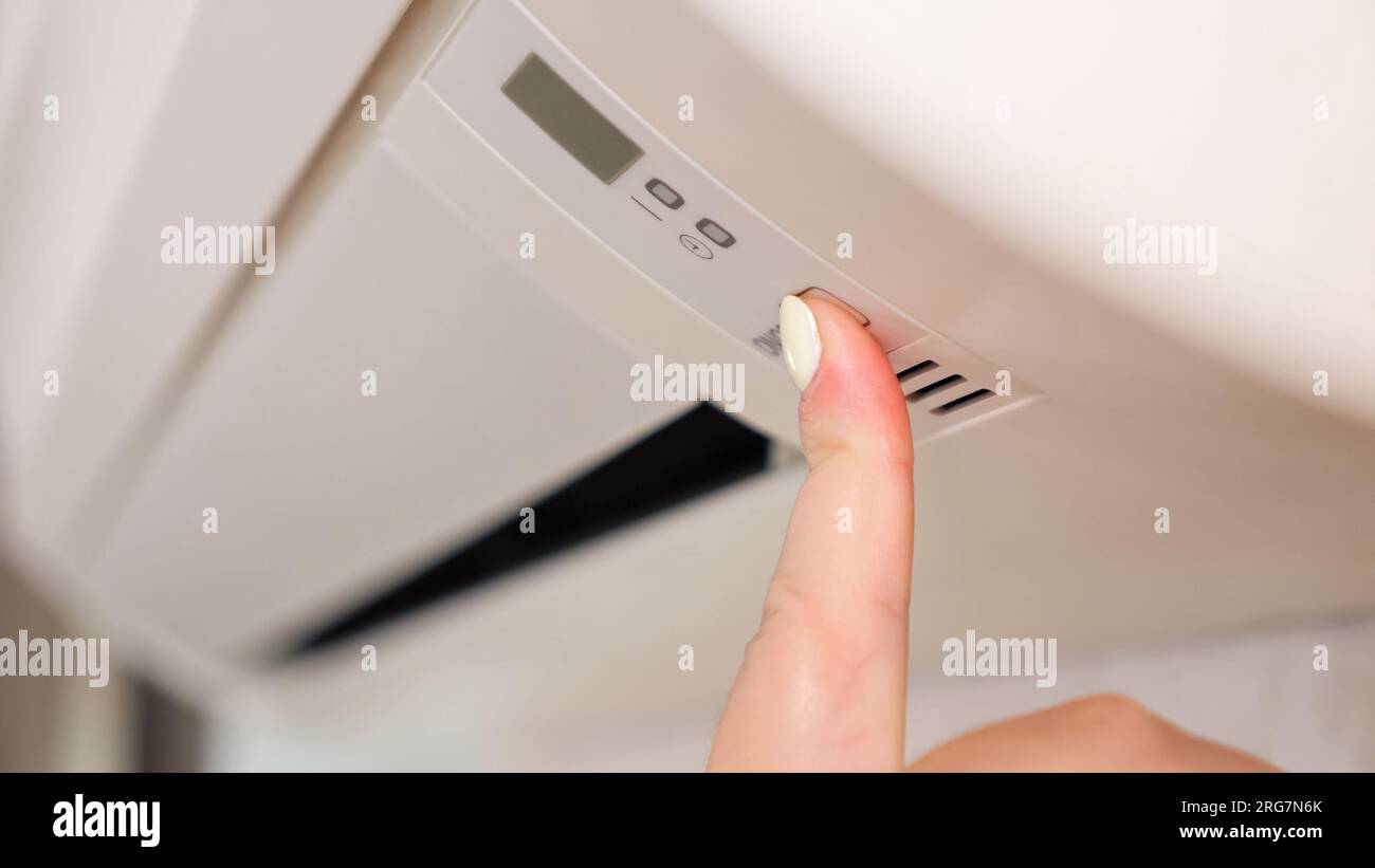 Woman hand presses button to turn on air conditioner Stock Photo - Alamy