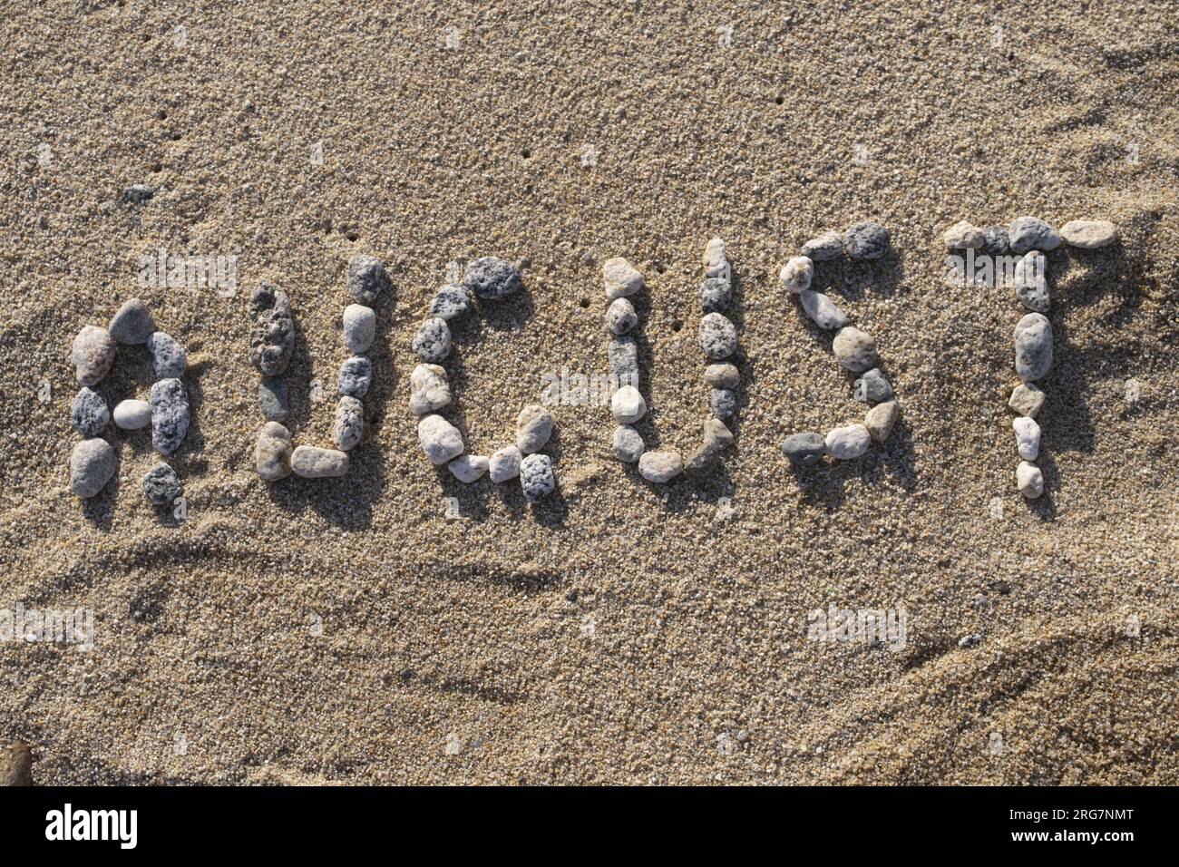august and summer concept with lettering made on a beach with stones ...
