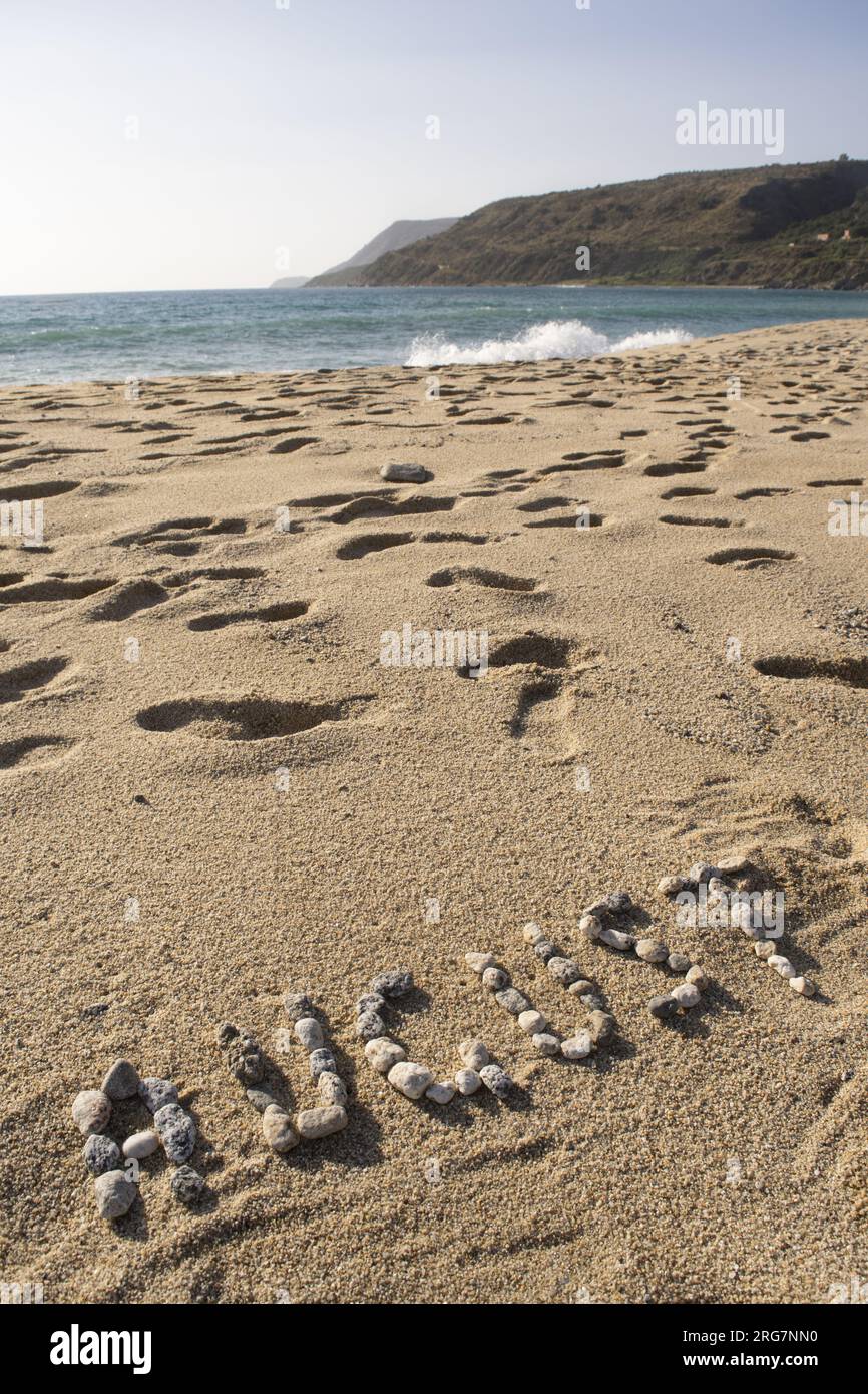 august and summer concept with lettering made on a beach with stones ...