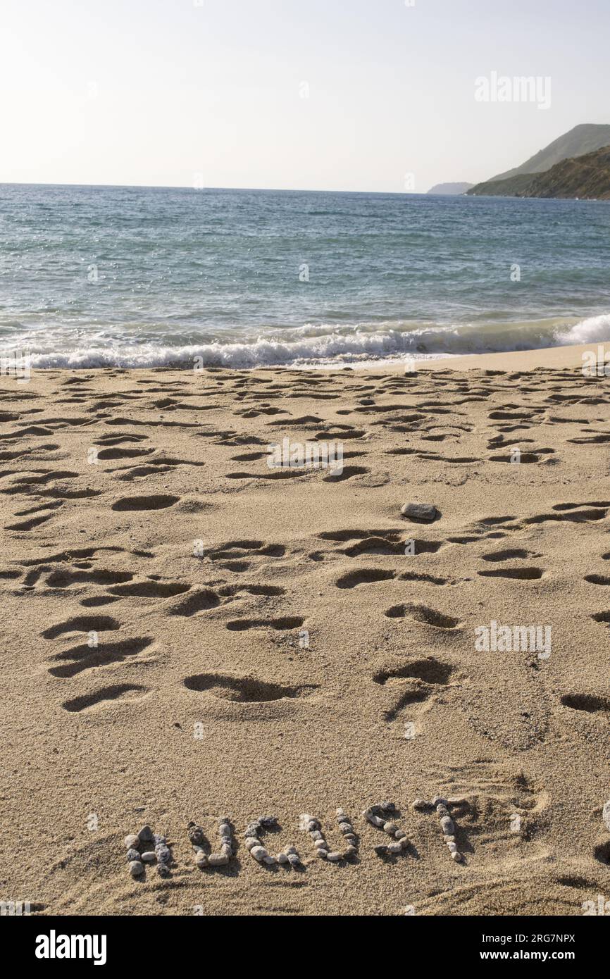 august and summer concept with lettering made on a beach with stones ...