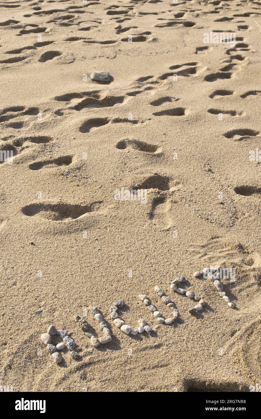august and summer concept with lettering made on a beach with stones ...